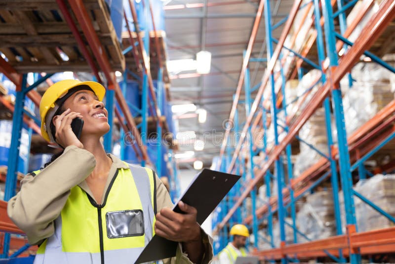 Female Worker Looking Up while Talking on Mobile Phone in Warehouse ...