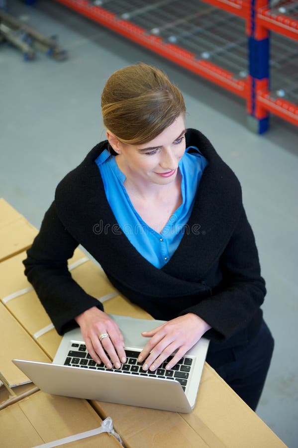 Female Worker Typing on Laptop Computer in Warehouse Stock Image ...