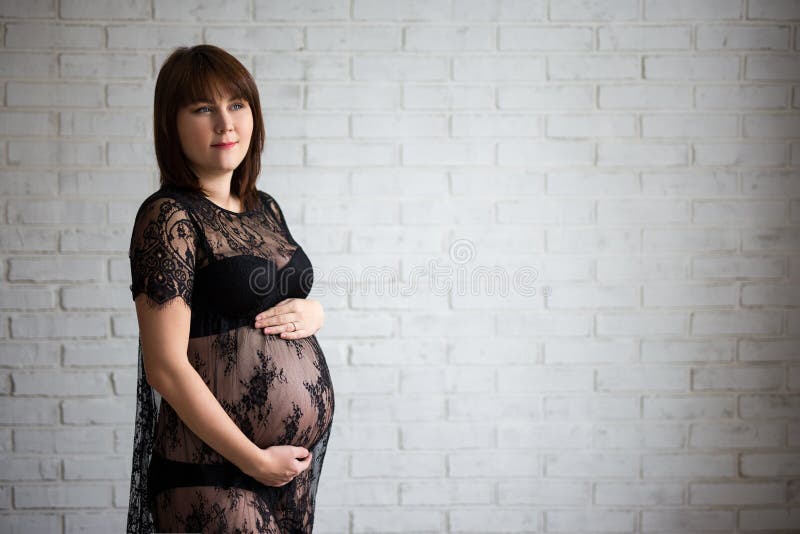 Femme Enceinte Heureuse Dans La Robe Noire De Dentelle Posant Au Dessus