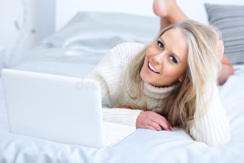 Femme De Sourire à Laide Dun Ordinateur Portable Se Trouvant Sur Son Lit Photo Stock Image