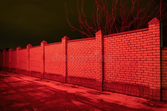 A Fence in the Form of a White Brick Wall is Illuminated with Red Light ...