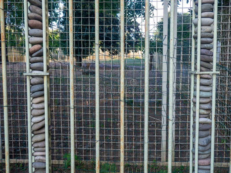 A Fence Made of Rods and Stacked Stones. Stacked Pebbles Stock Image ...