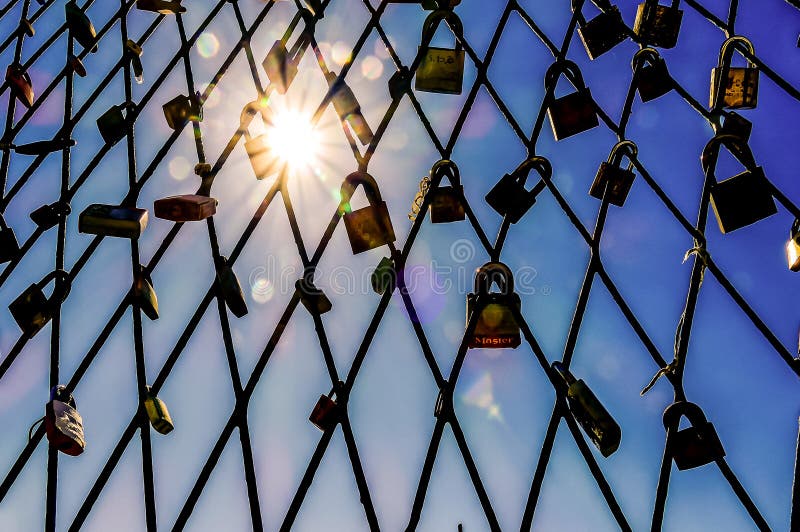 A Fence with Many Locks on it and a Sun Shining on it Stock Photo ...