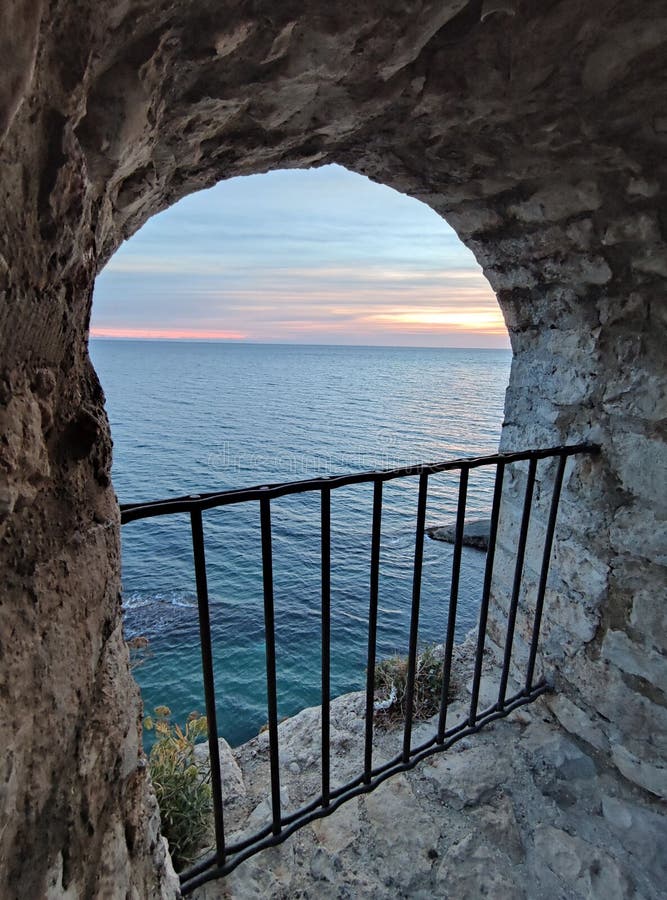 Fenced Arch Opening through the Rock Overlooking the Sea during Bright ...