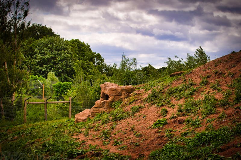 Fenced Outdoor Area with Grassy Hill and Rocky Structure Stock Image ...