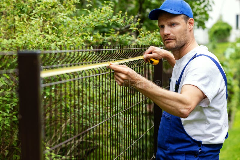 Fencing Services. Worker Taking Measurements with Measuring Tape Stock ...