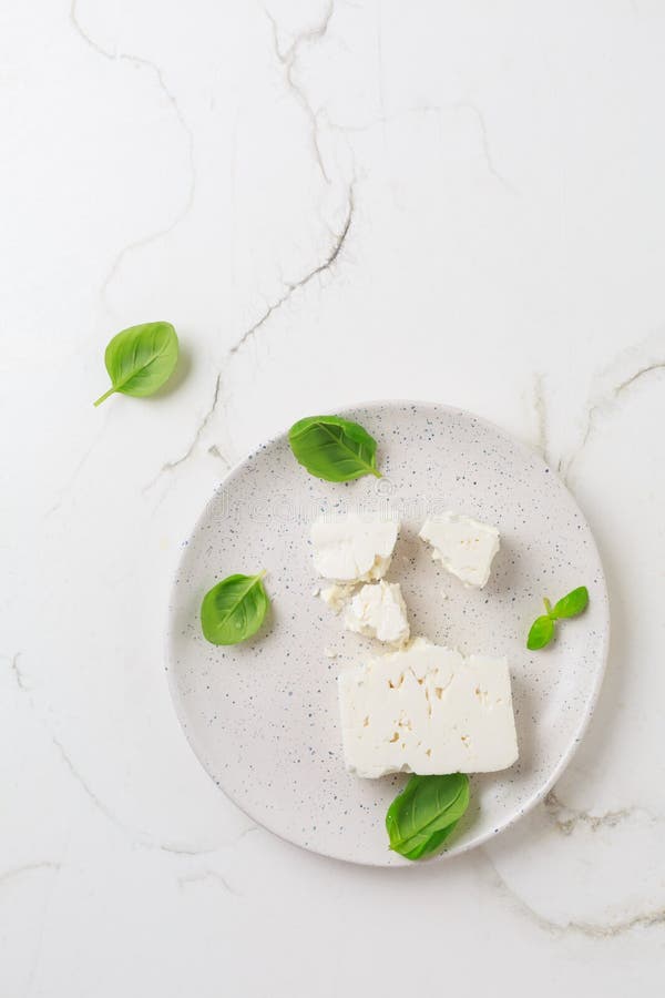 Feta Cheese with Basil Leaves on Plate and White Background Stock Photo ...
