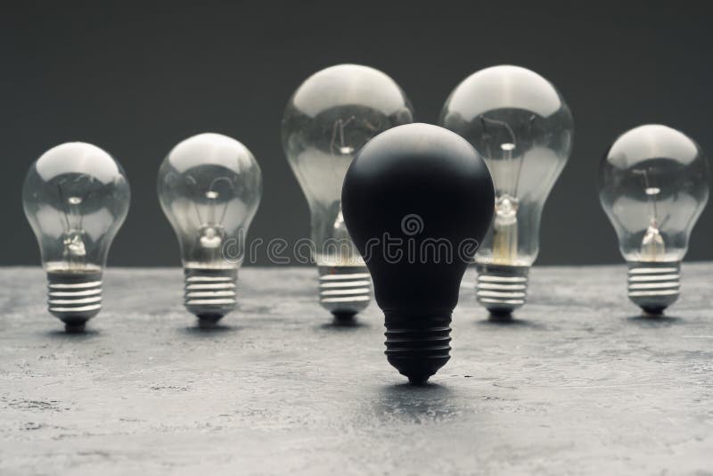 Burned Light Bulbs and One Black Light Bulb on a Gray Concrete ...