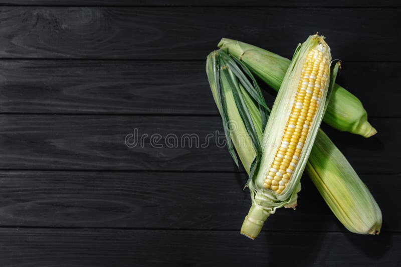 A Few Corn in Leaves Lie on a Wooden Dark Background. View from Above ...
