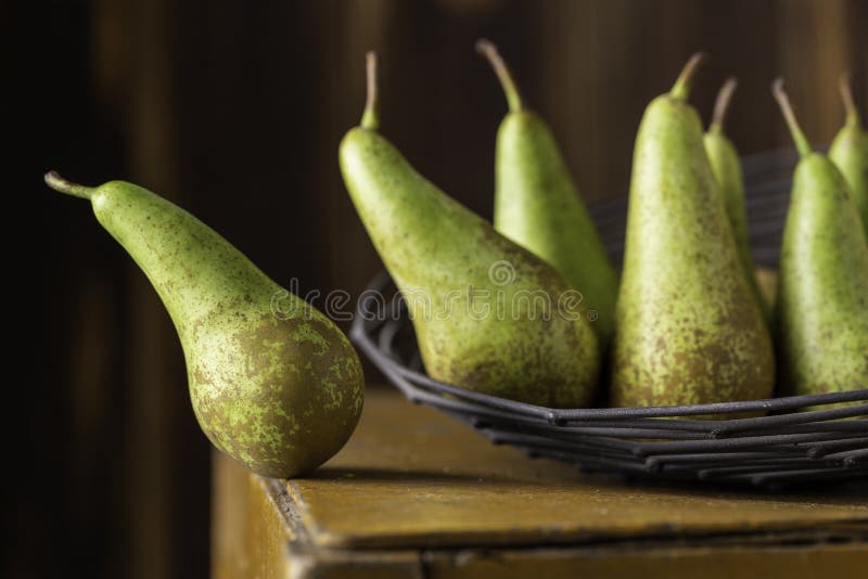 A Few Ripe Pears in a Basket on an Old Table, with One of Them Falling ...