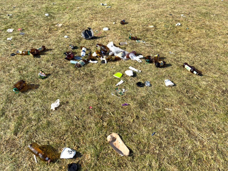 A Field is Littered with Trash, Including Bottles and Other Garbage ...