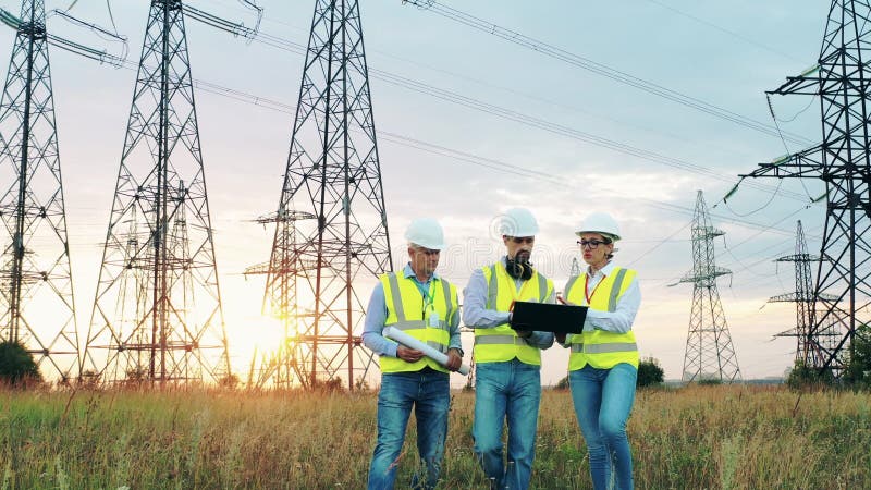 Field with Transmission Towers with Engineers Walking Along it Stock ...