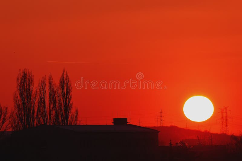 Fiery Red Sunset Disk Behind Silhouetted Trees and Building Stock Photo - Image of sunset, calm ...