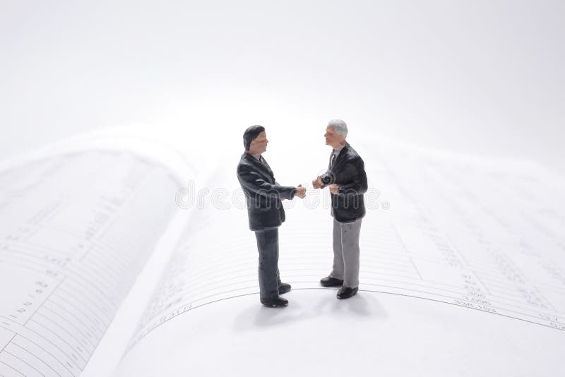 A Figure of Business People Shaking Hands on the Book Stock Image ...