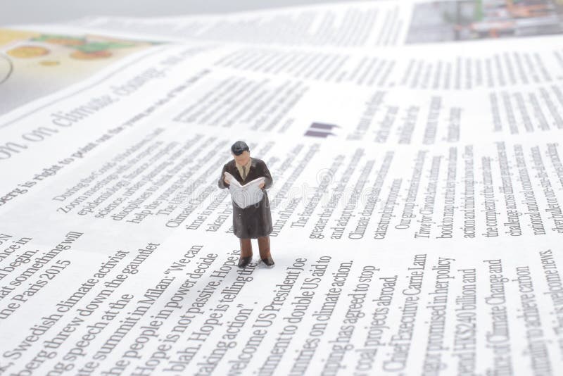 A Figure of a Man Reading a Newspaper while on a Full Size Newspaper ...