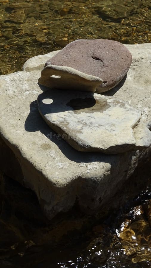 A Figure of Stacked Stones with a Round Hole in a Ray of Sun and Shadow ...