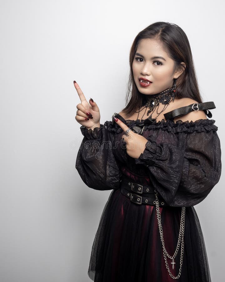 Filipina In A Vampire Costume Pointing To The Side With Index Fingers On White Background Stock