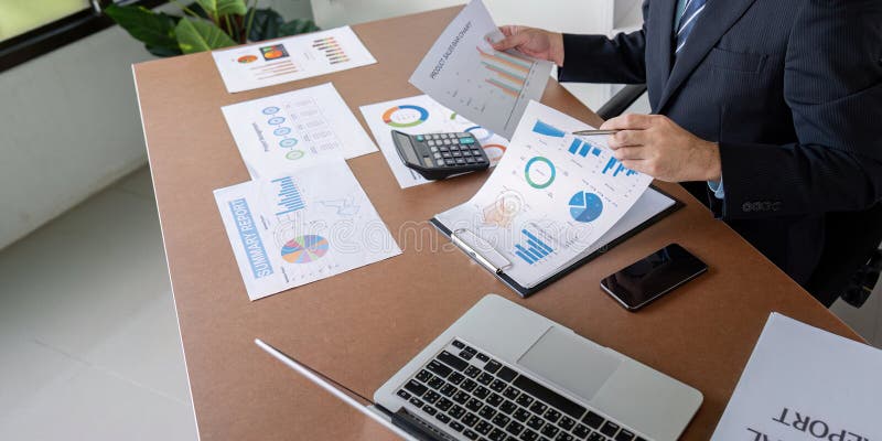 Financial Analyst Reviewing Charts and Graphs from Reports in a Modern ...