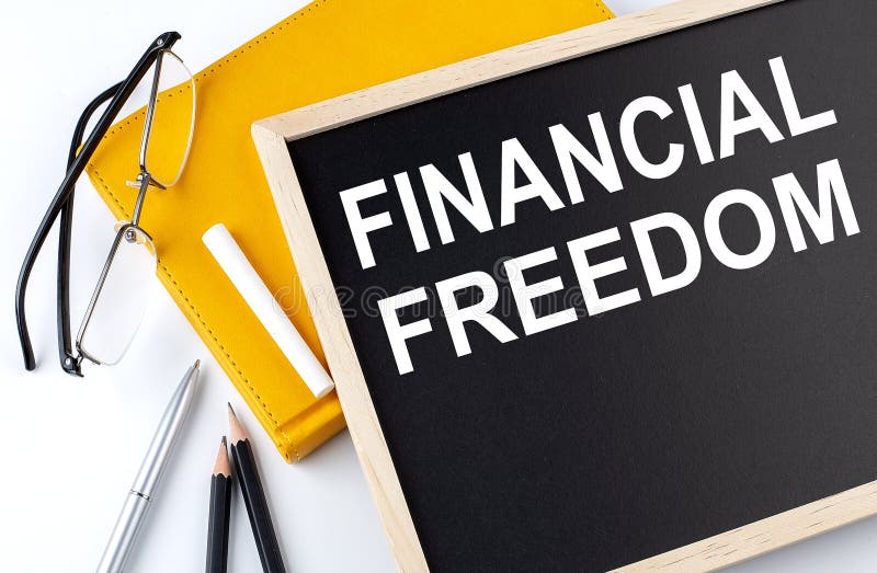 FINANCIAL FREEDOM Text on the Blackboard with Notepad , Pen, Pencil ...