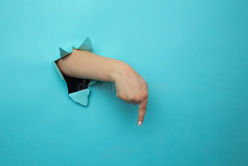 Finger Pointing Down through Torn Blue Paper Wall. Hand Gestures of ...