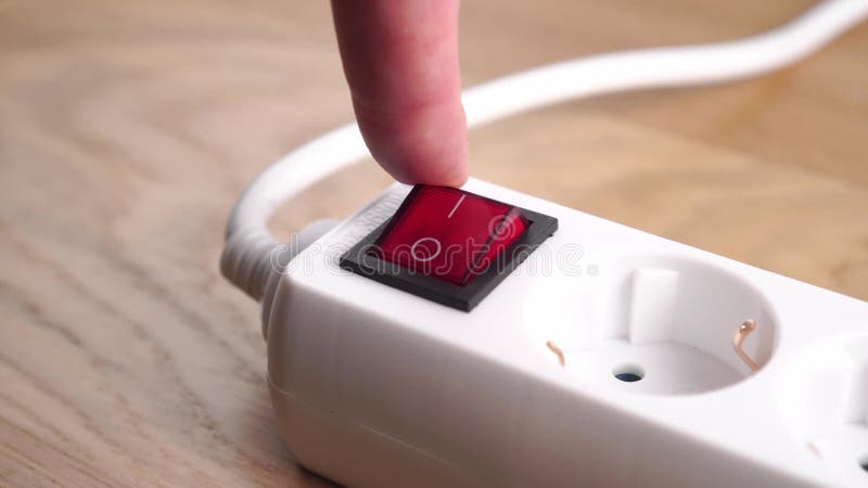Finger Pressing the Red Button Switch of the White Electric Power Strip ...