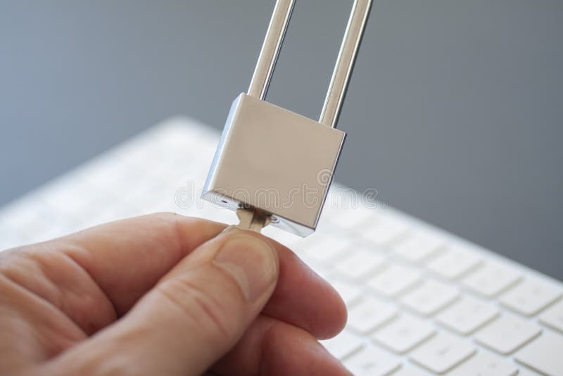 Fingers Turning a Key on Stainless Padlock in Front of Computer ...