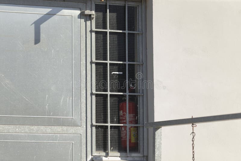 A Fire Extinguisher is Located Behind a Window that Has Bars on it ...