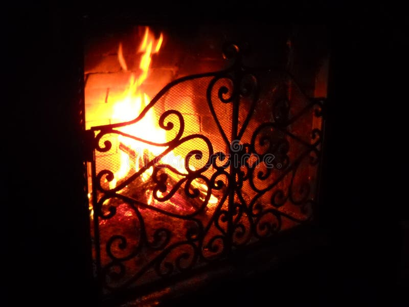 Fire in the Fireplace Behind a Beautiful Wrought Iron Grate with Curls ...
