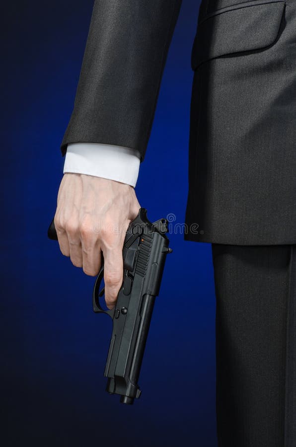 Firearms and Security Topic: a Man in a Black Suit Holding a Gun on a ...