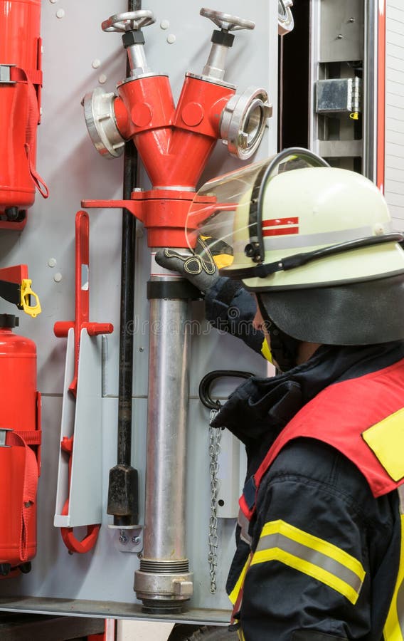 A Fireman with water hose stock photo. Image of call - 53472056