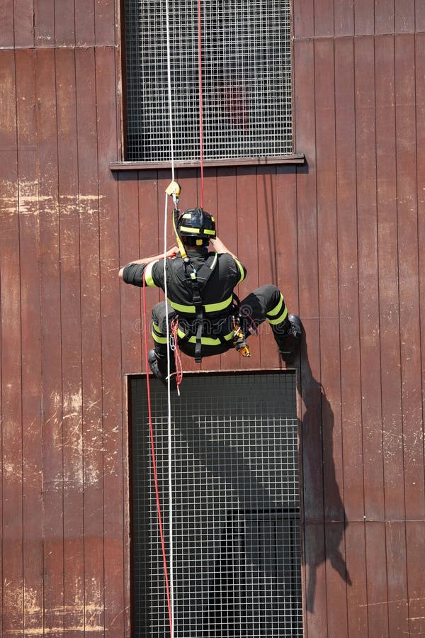 Firefighter in Helmet and Uniform Rappelling Down Building during Fire ...