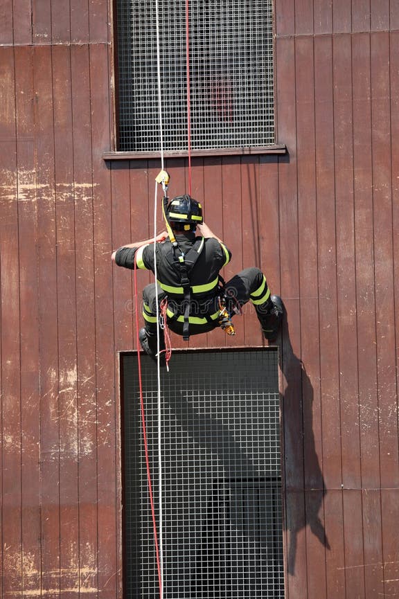 Firefighter in Helmet and Uniform Rappelling Down Building during Fire ...