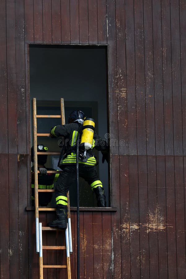 Firefighter with an Oxygen Tank Climbing a Ladder during a Training ...
