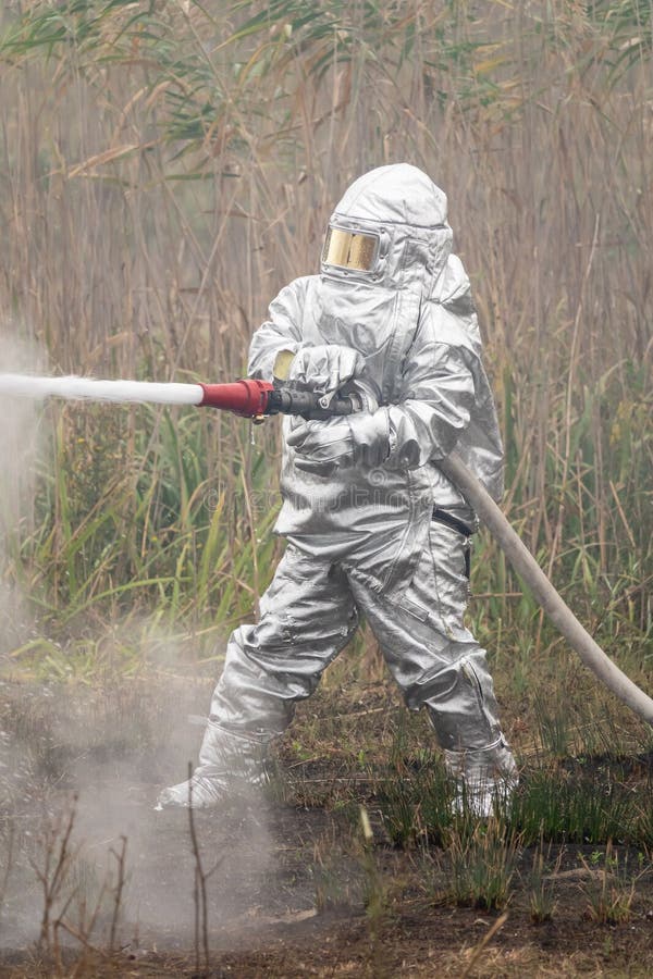 Firefighter in Protective Suit Works with Water Hose. Fighting for a ...
