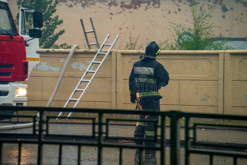 Firefighter Rear View at Wall with Ladders and Fire Engine at Scene of ...