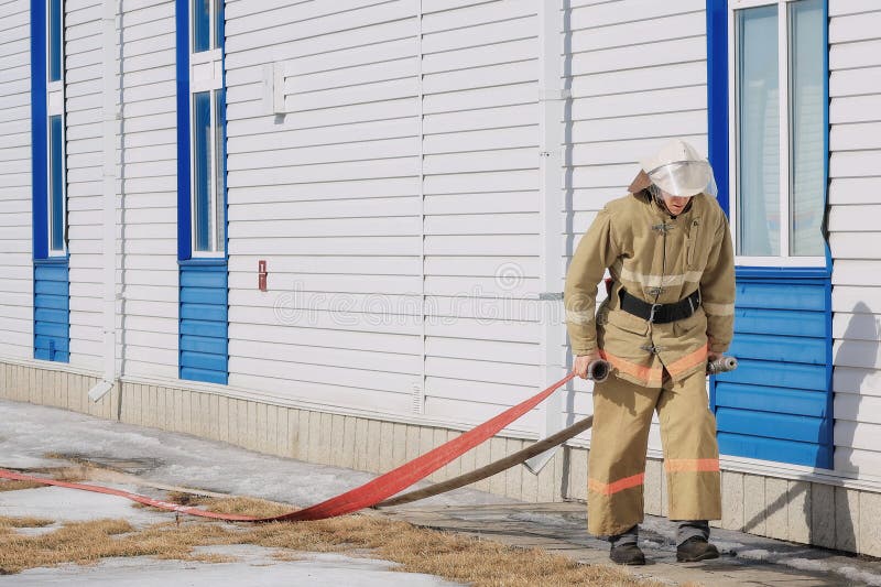 Firefighter Rolling a Hose Near Building Stock Image - Image of hero ...