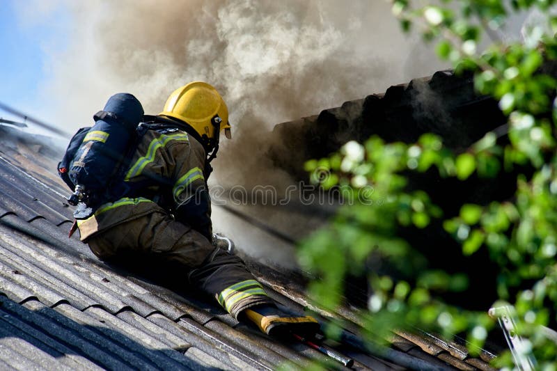 A Firefighter on the Roof of a House Extinguishes a Fire Stock Photo ...