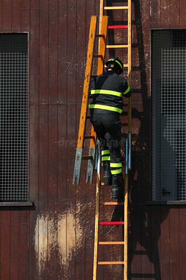 Firefighter in Uniform with Helmet Climbing Ladder during Training at ...