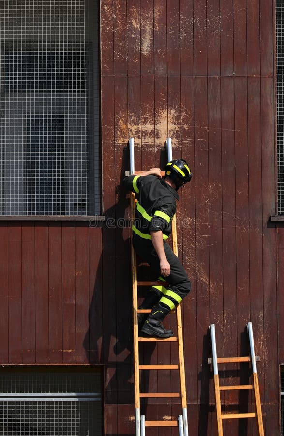 Firefighter in a Uniform and Helmet is Setting Up a Ladder during a ...