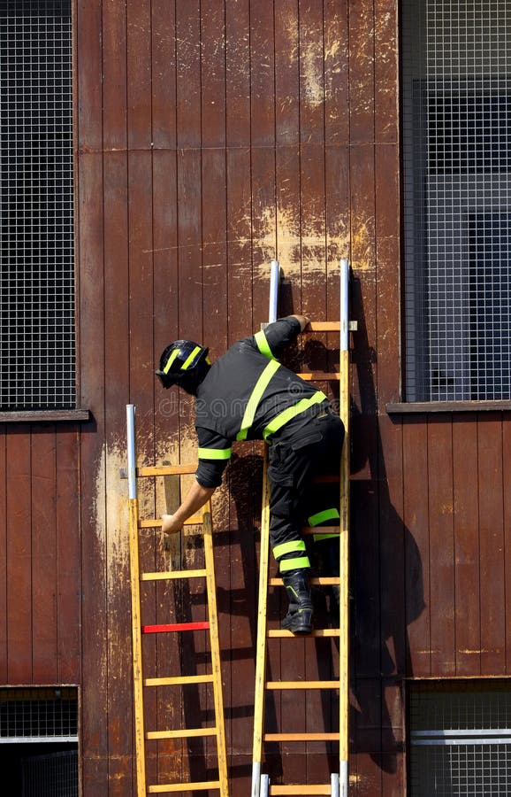 Firefighter in a Uniform and Helmet is Setting Up a Ladder during a ...