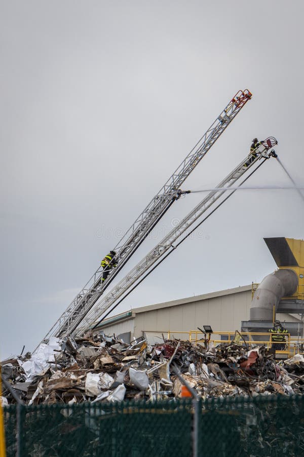 Firefighter Using Hose from a Ladder at an Industrial Fire Stock Image ...