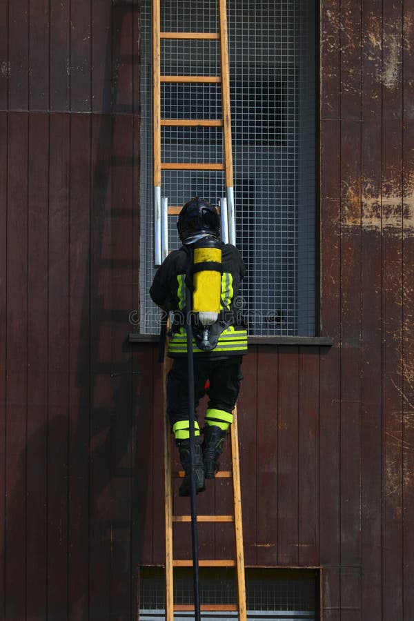 Firefighter Wearing an Oxygen Tank Climbs a Ladder during a Training ...