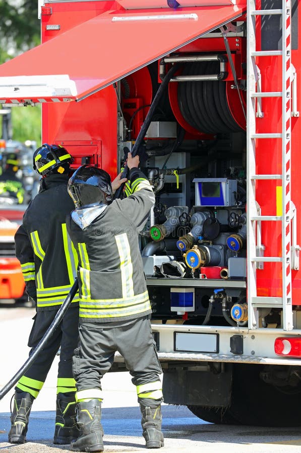 Firefighters Wearing Uniforms Take the Fire Hose from the Red Fire ...