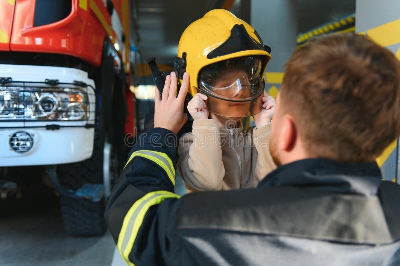 A Fireman Shows His Work To His Young Son. a Boy in a Firefighter S ...
