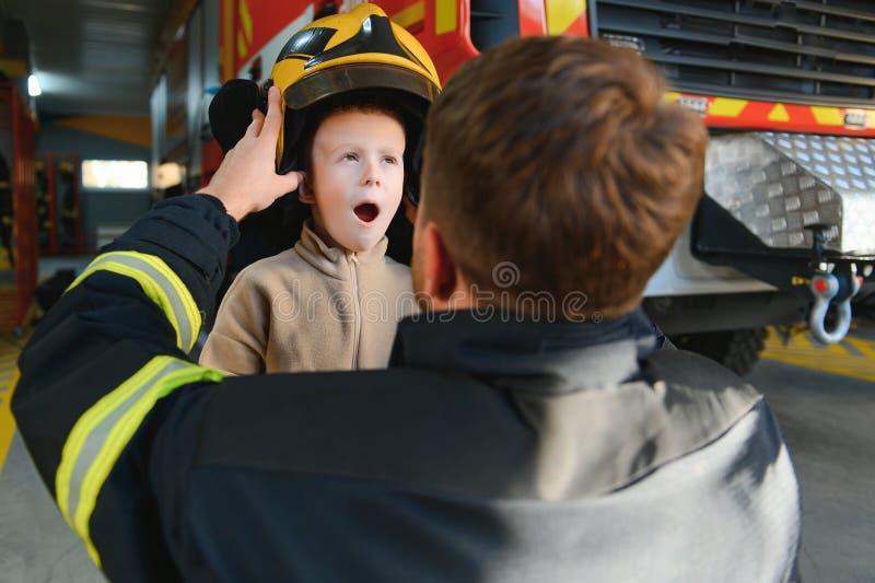 A Fireman Shows His Work To His Young Son. a Boy in a Firefighter& X27 ...