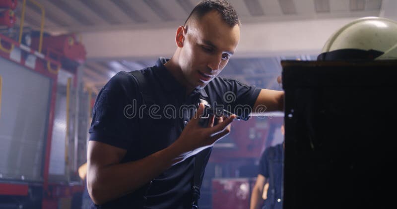 Fireman Using Smartphone and Talking with Colleague Stock Photo - Image ...