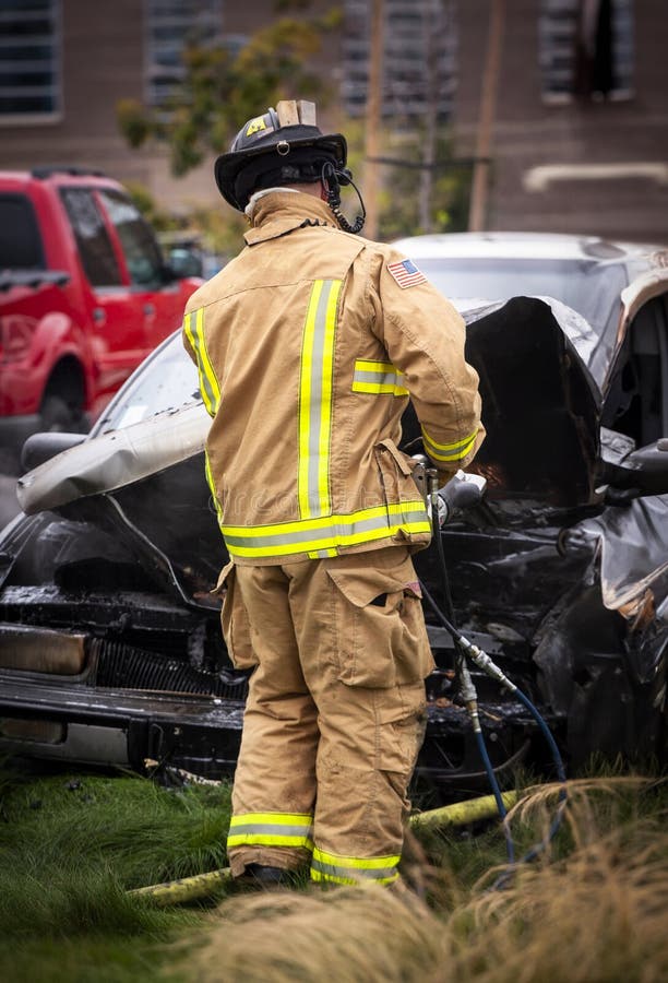 Fireman Working at Scene of Burned Car Wearing Protective Clothing ...