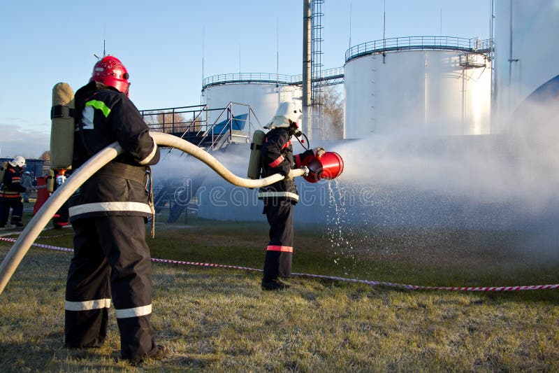 Firemen Extinguish Fire at Oil Tanks by Foam Spraying Hose Stock Image ...