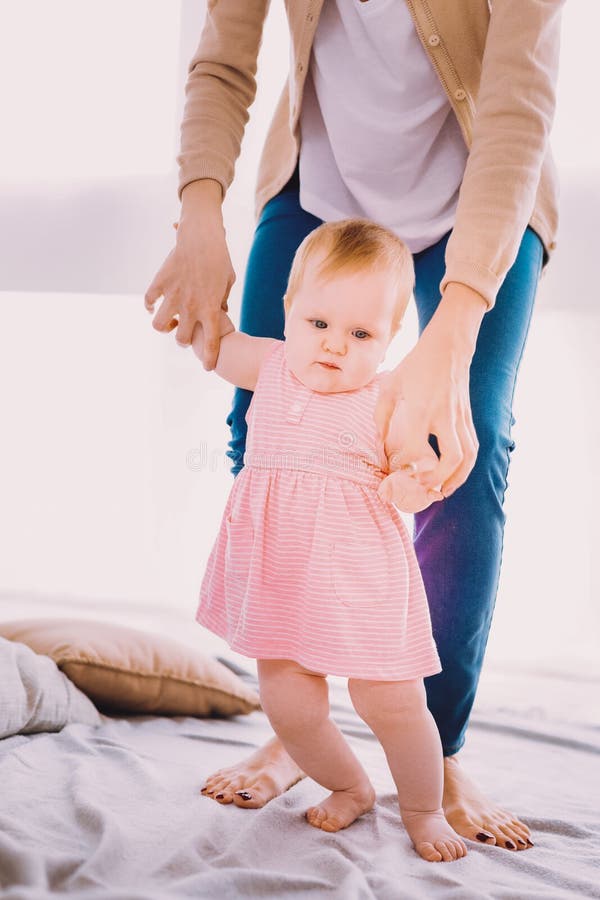 Concentrated Baby Learning To Walk and Her Mother Helping Her Stock ...