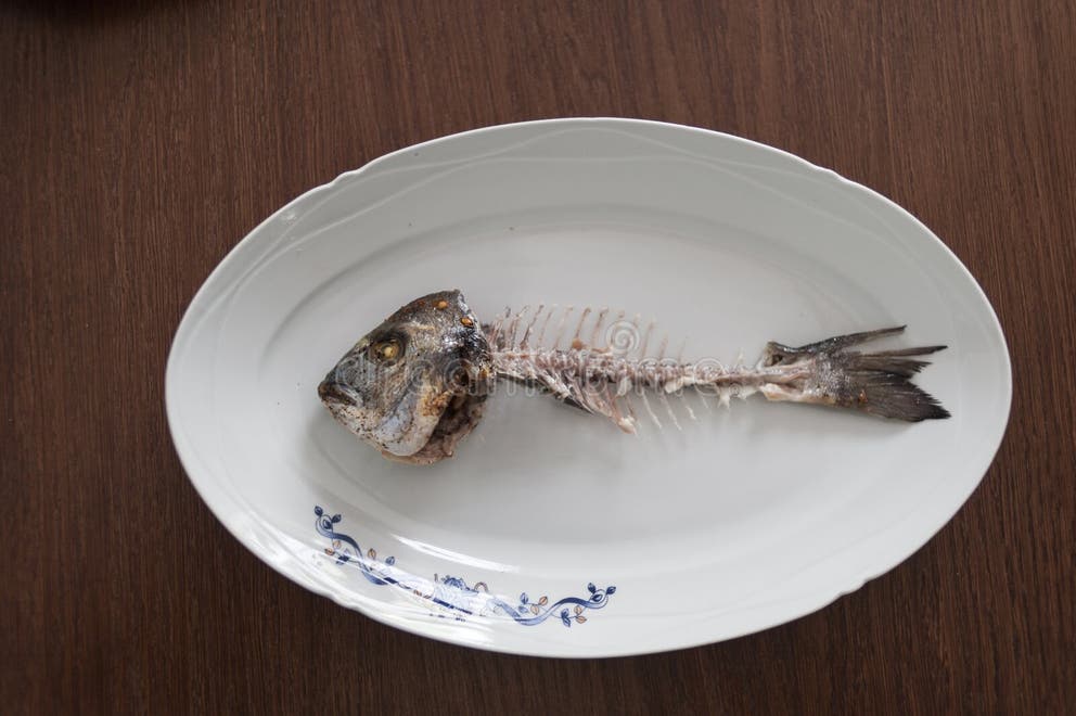Fish Bone Left Overs with a Sliced Lemon on a White Oval Plate. Stock ...
